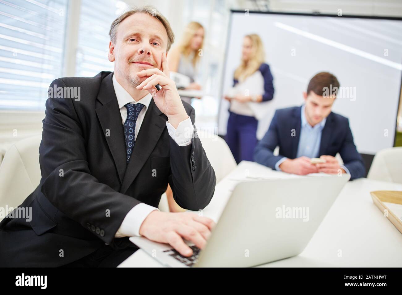 Older businessman using computer in business meeting Stock Photo - Alamy