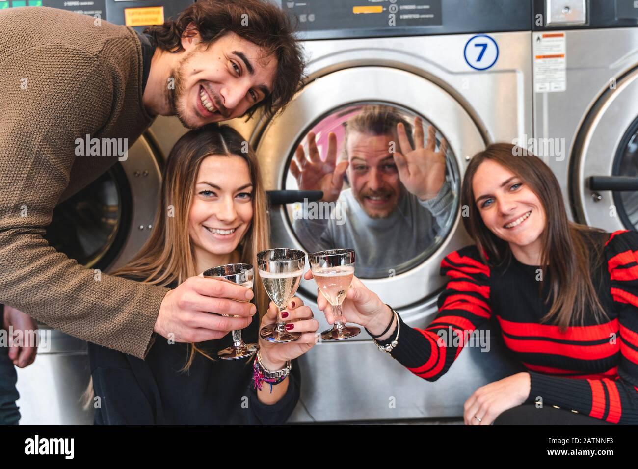 group of friends are toasting with white wine to a party in the laundry ...