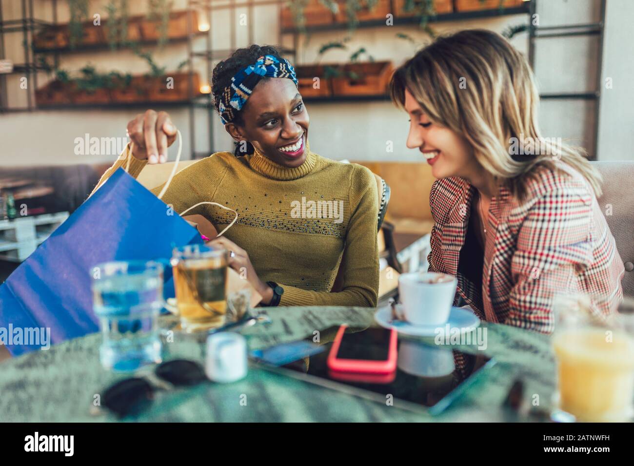 Two female friends talking at a coffee shop, after shopping Stock Photo ...