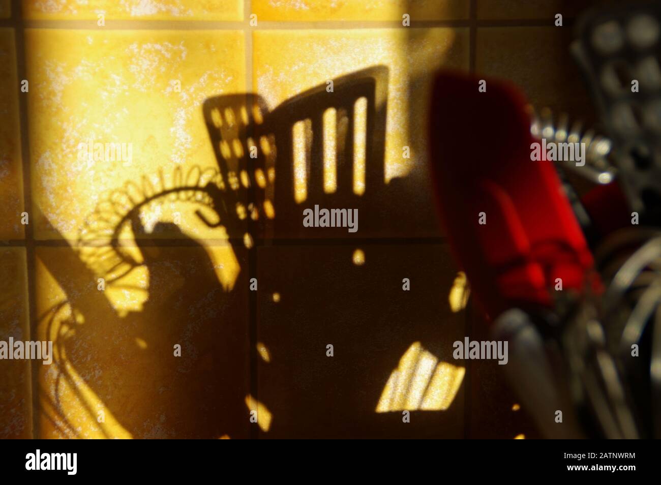 Kitchen tools that cast a shadow on the ceramic wall. Morning in the ...