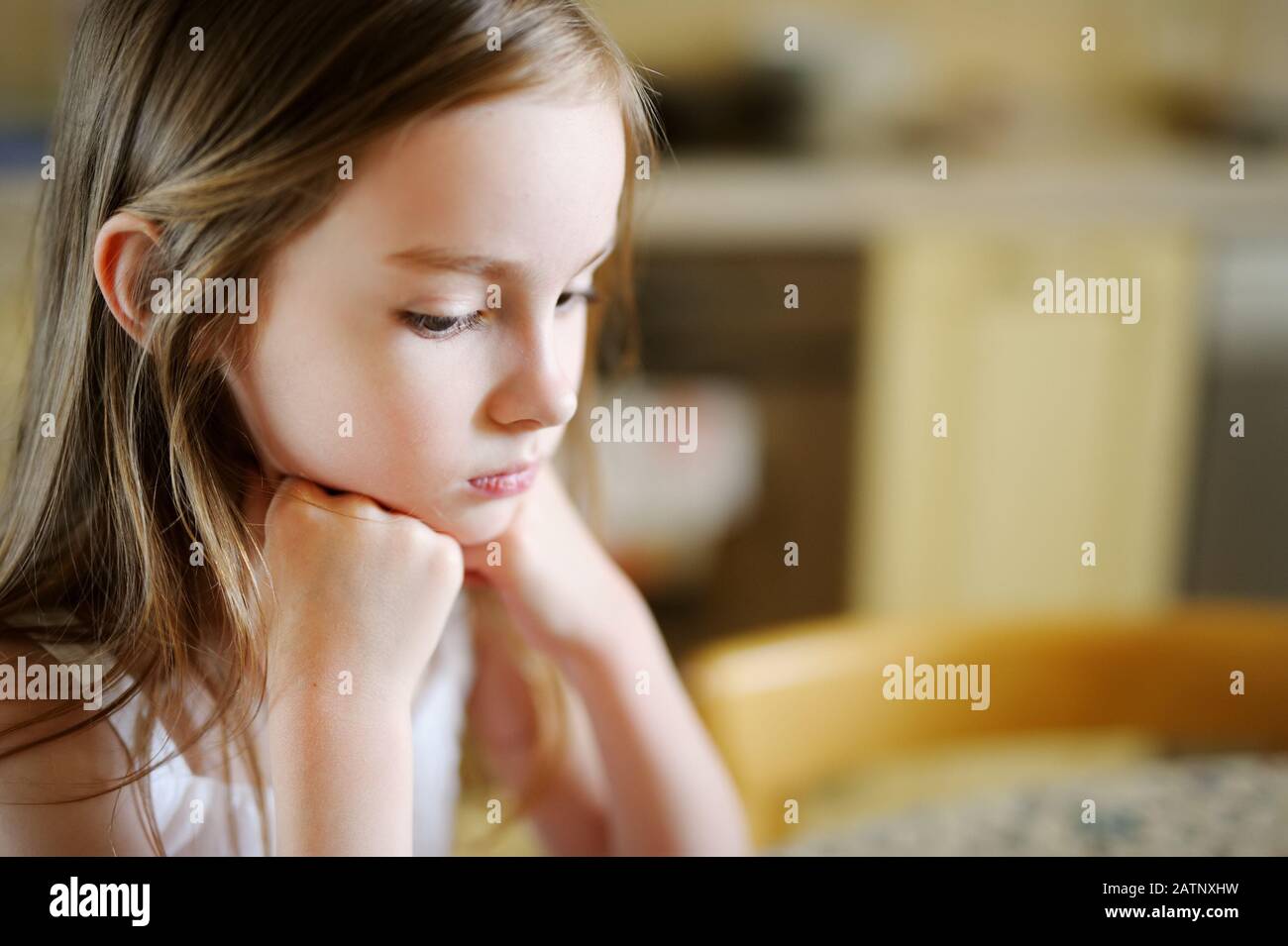 Bored little girl sitting by the table. Sad tired child at home Stock ...