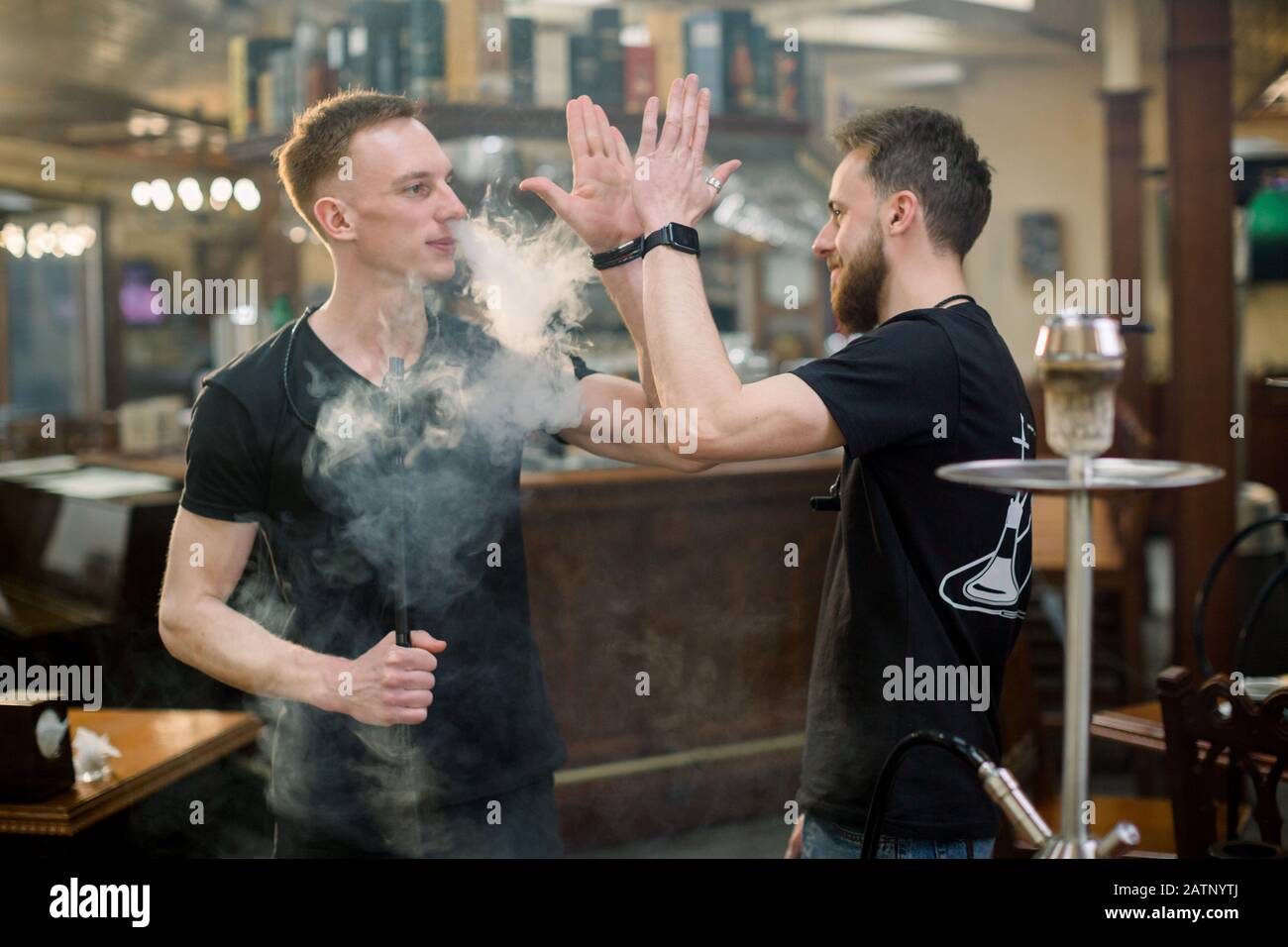 Two young hookah masters prepare the Shisha in traditional cozy cafe ...
