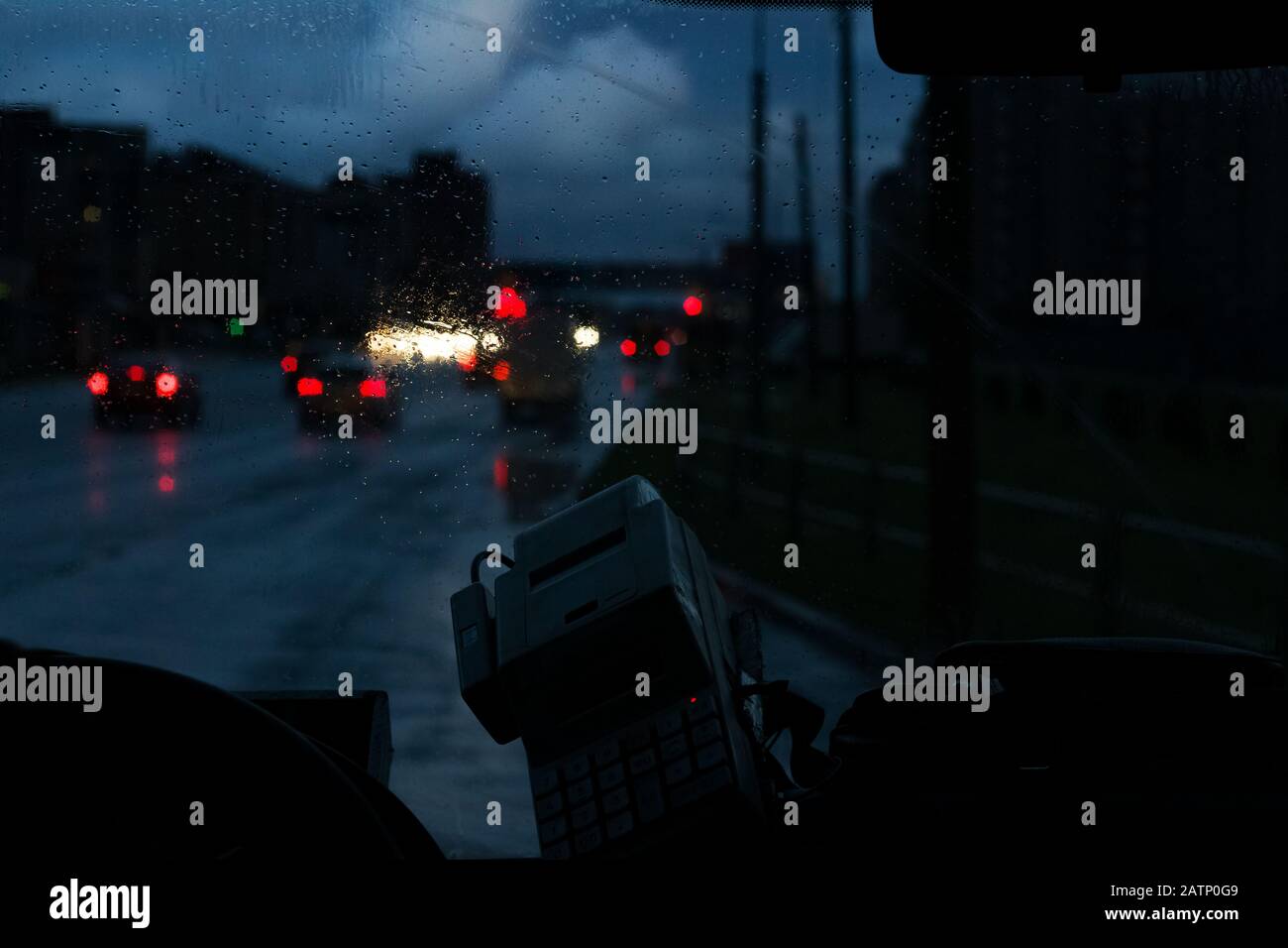 Car front window with raindrops and road with cars at night close up ...