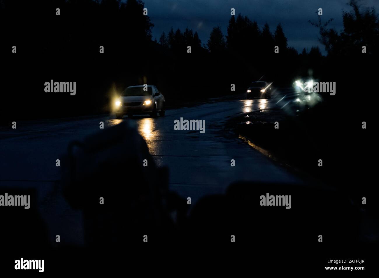 Car front window with raindrops and road with cars at night close up ...