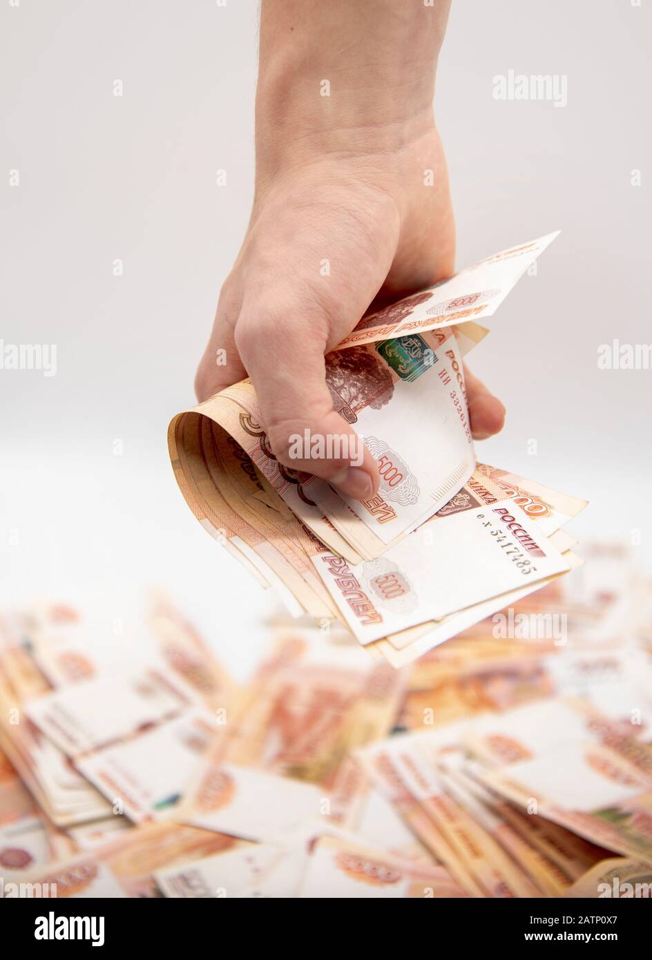 A man holds a stack of five-thousand-ruble bills in the palm of his ...