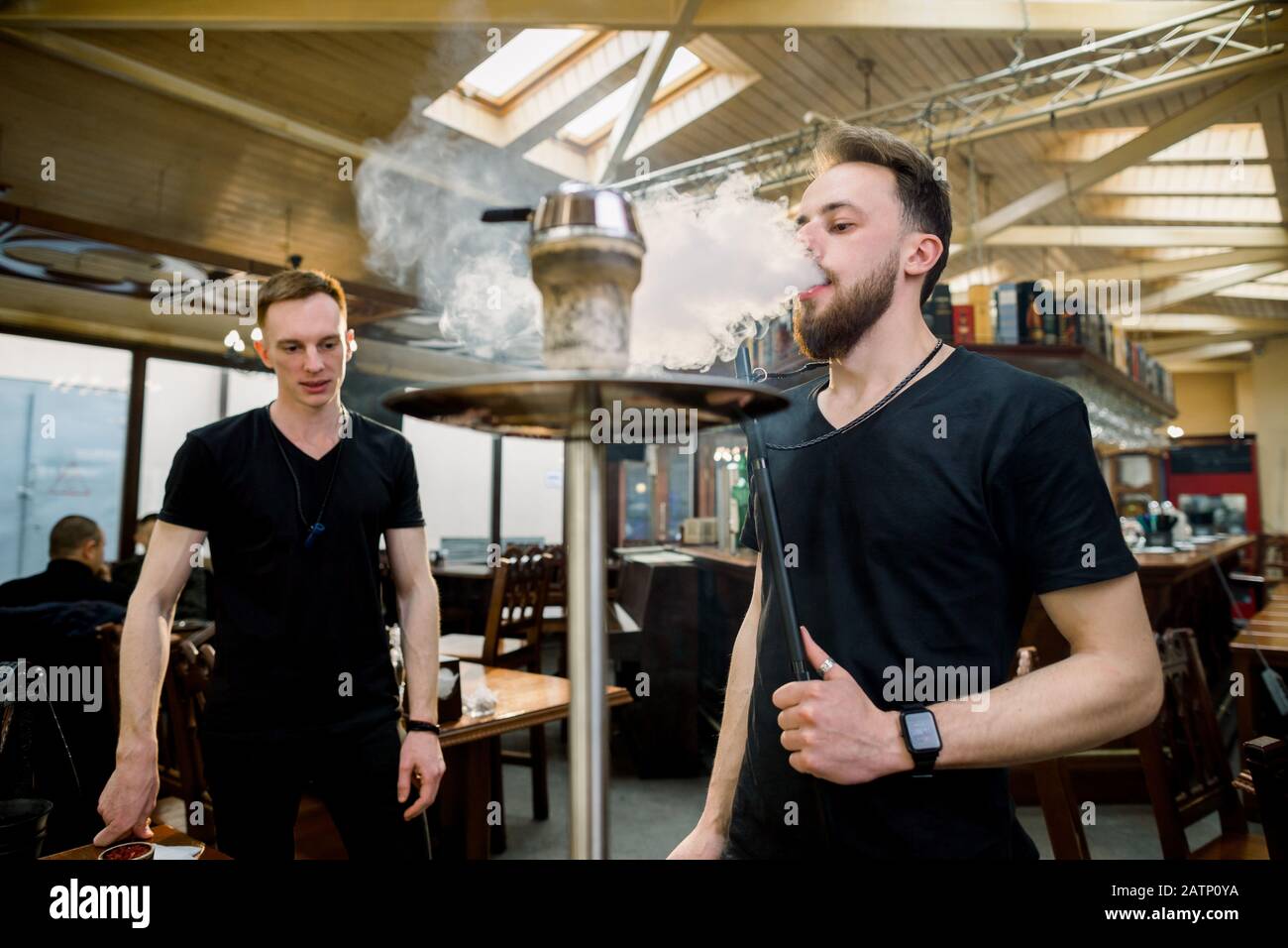 Two young boys preparing shisha by placing the charcoals on top. One ...