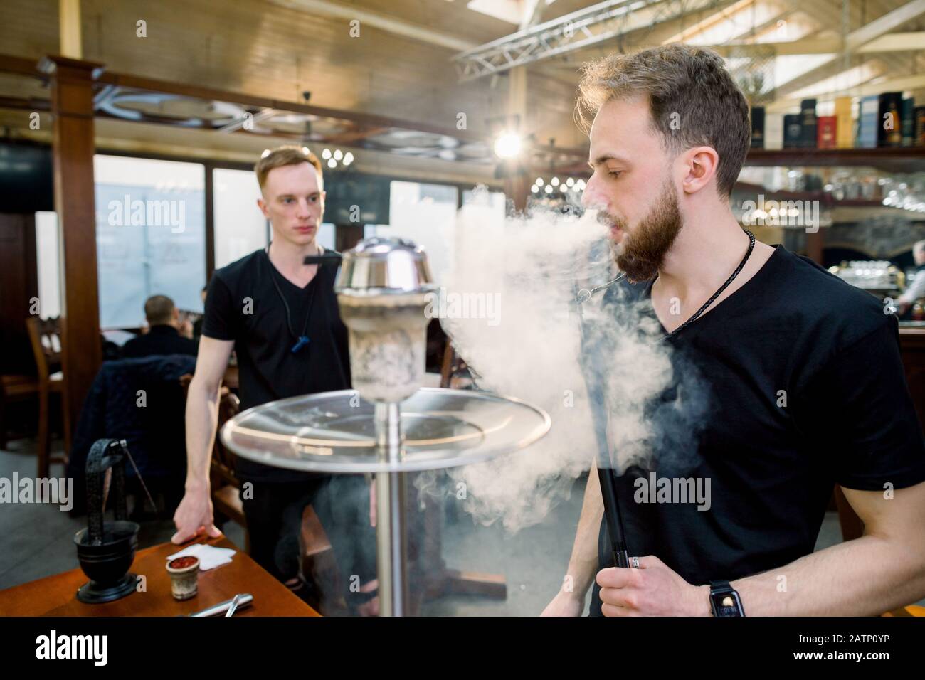 Two young boys preparing shisha by placing the charcoals on top. One ...