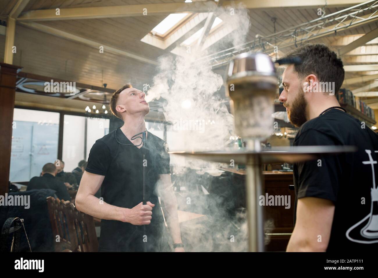 Two young hookah masters prepare the Shisha in traditional cozy cafe ...