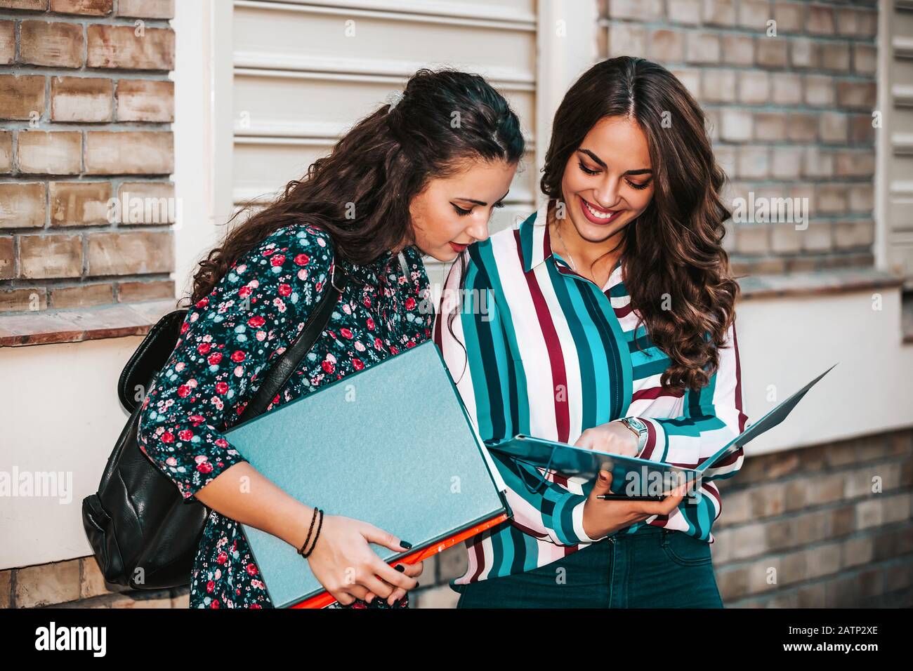 Two beautiful female friends, students checking paper notes before exam ...