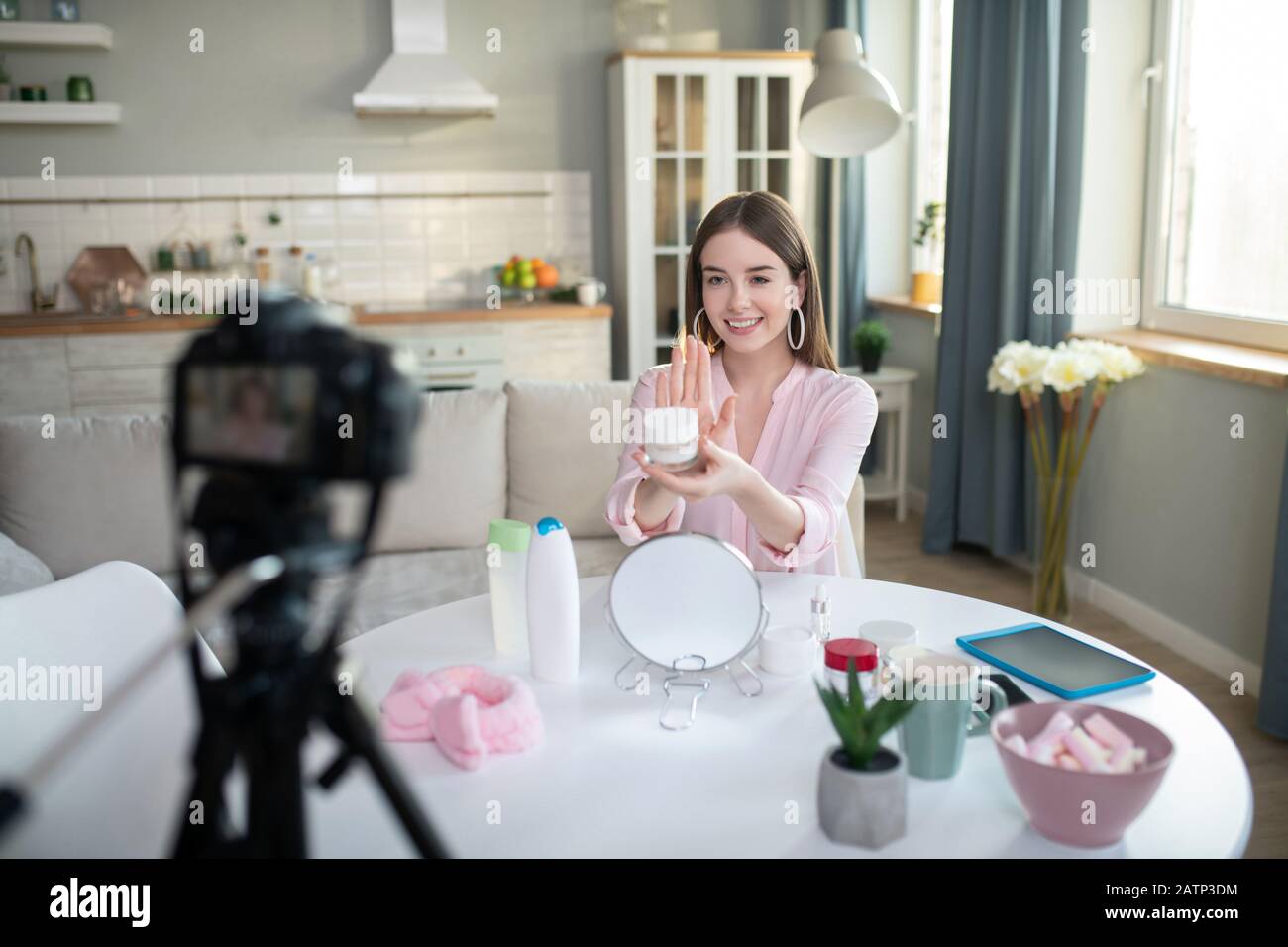 Cute young girl in a pink shirt explaining online how to use new cream ...