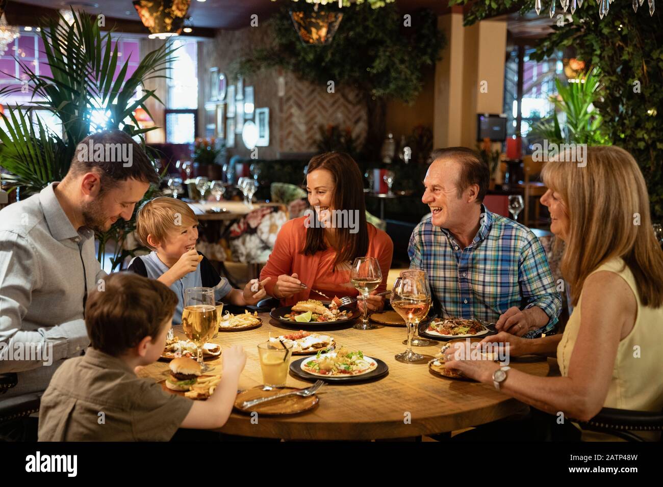 A family having a meal at a restaurant. They are laughing with each ...