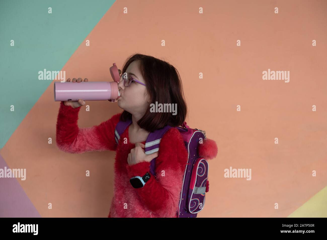 girl with cup. schoolgirl girl in glasses drinks water from a thermomug ...