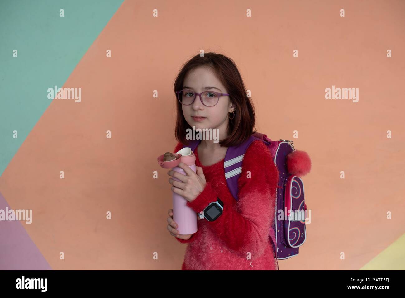 girl with cup. schoolgirl girl in glasses drinks water from a thermomug ...
