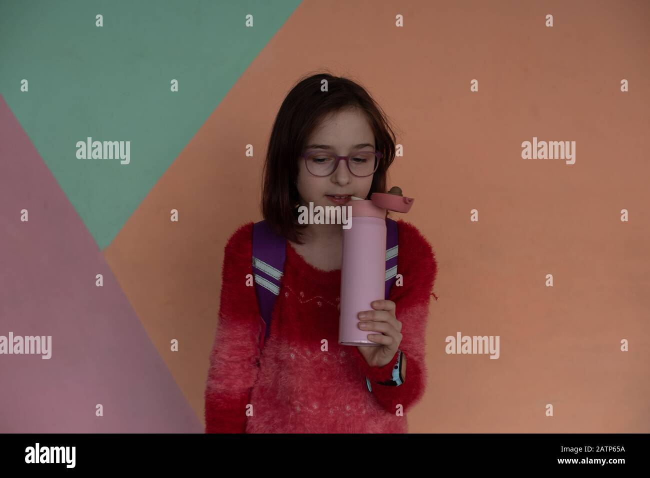 girl with cup. schoolgirl girl in glasses drinks water from a thermomug ...