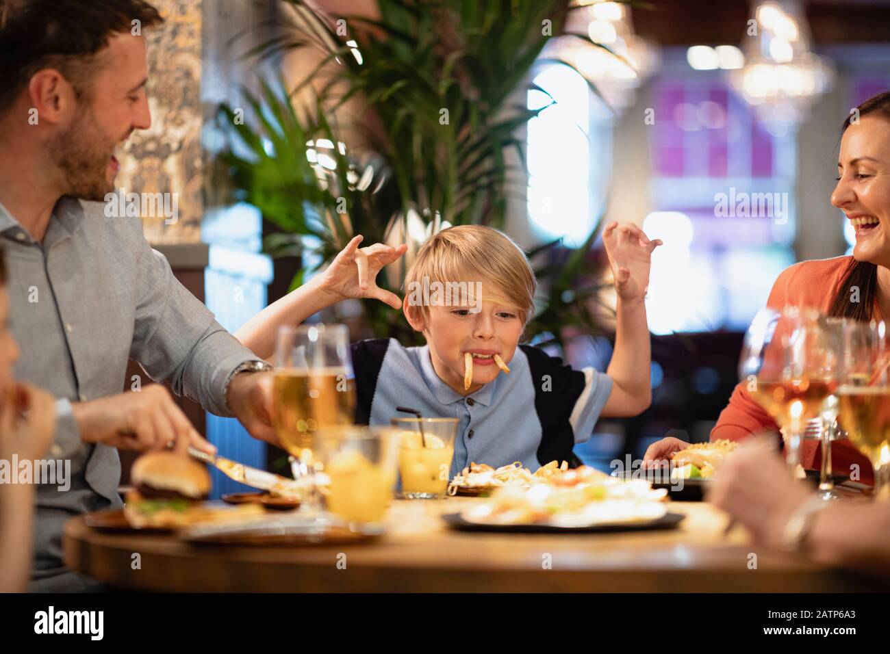 A family having a meal at a restaurant. A young boy is making them all ...