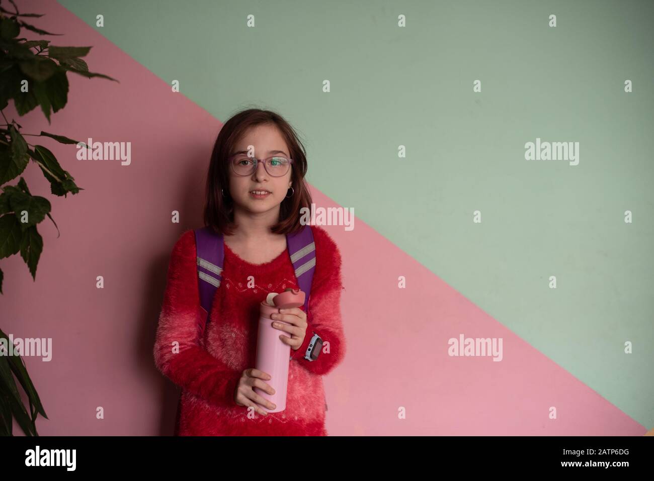 girl with cup. schoolgirl girl in glasses drinks water from a thermomug ...