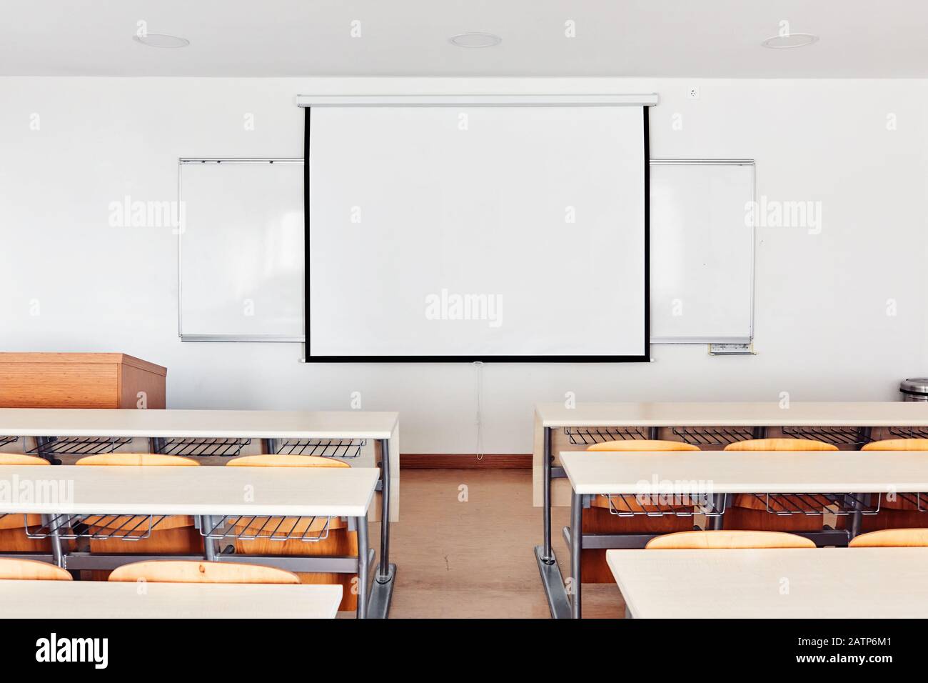 Classroom interior with white board, projection screen and wooden desks ...