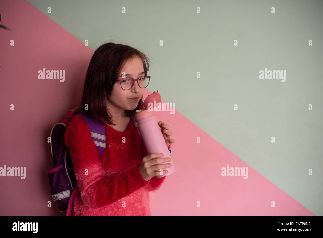 girl with cup. schoolgirl girl in glasses drinks water from a thermomug ...