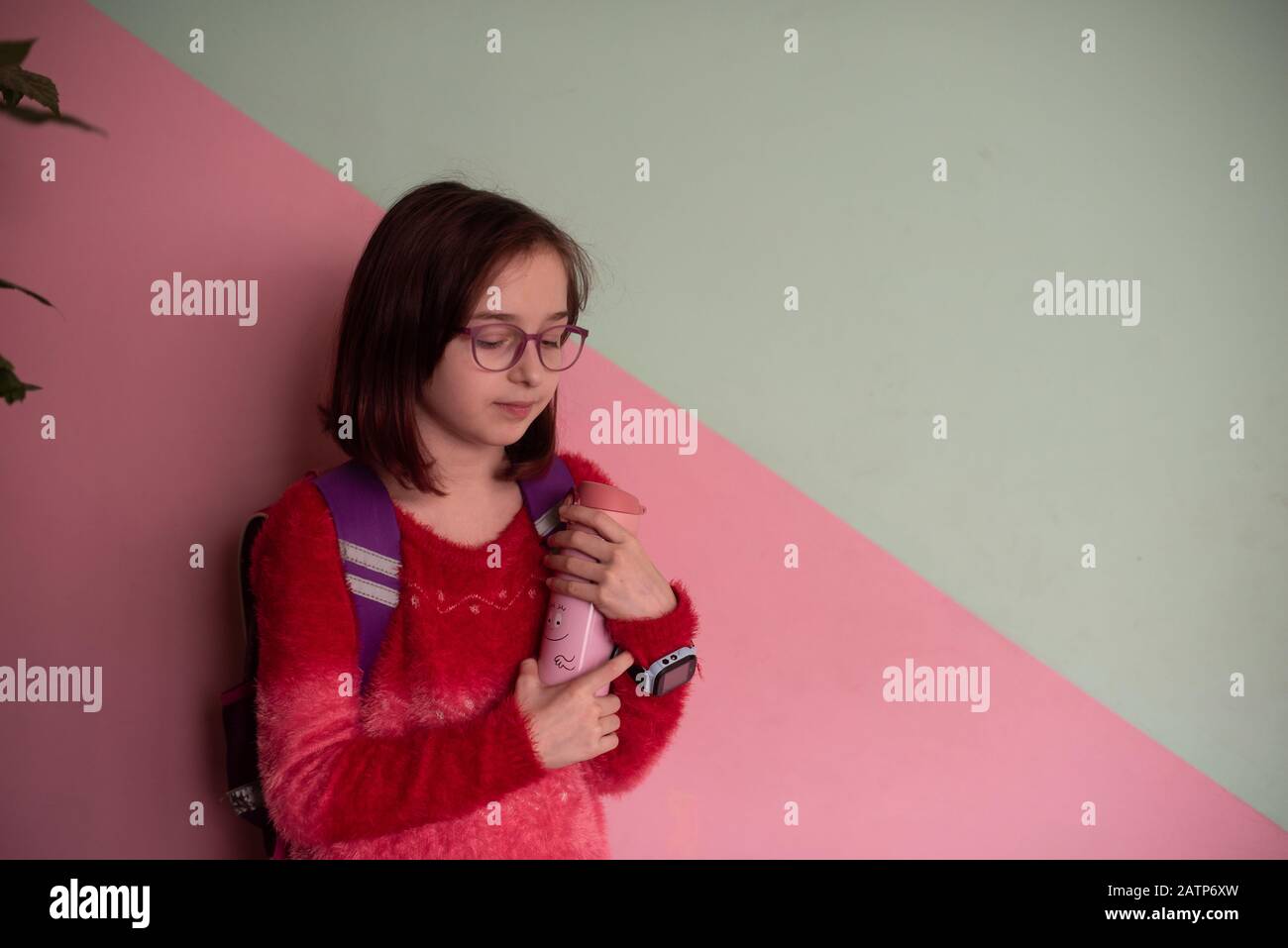 girl with cup. schoolgirl girl in glasses drinks water from a thermomug ...