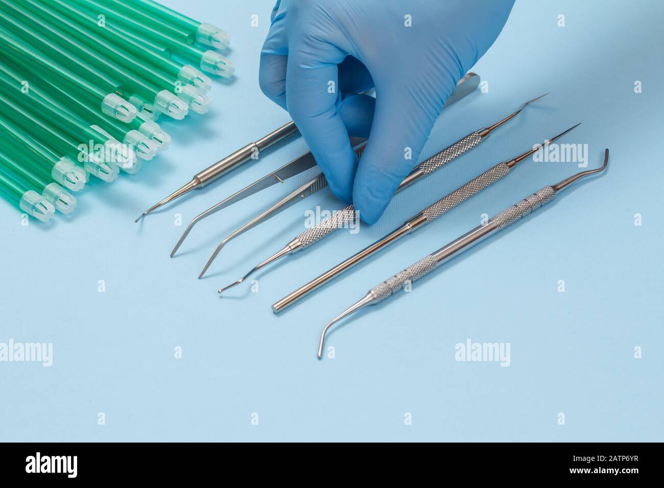 Dentist's hand in a rubber glove and set of metal dental instruments ...