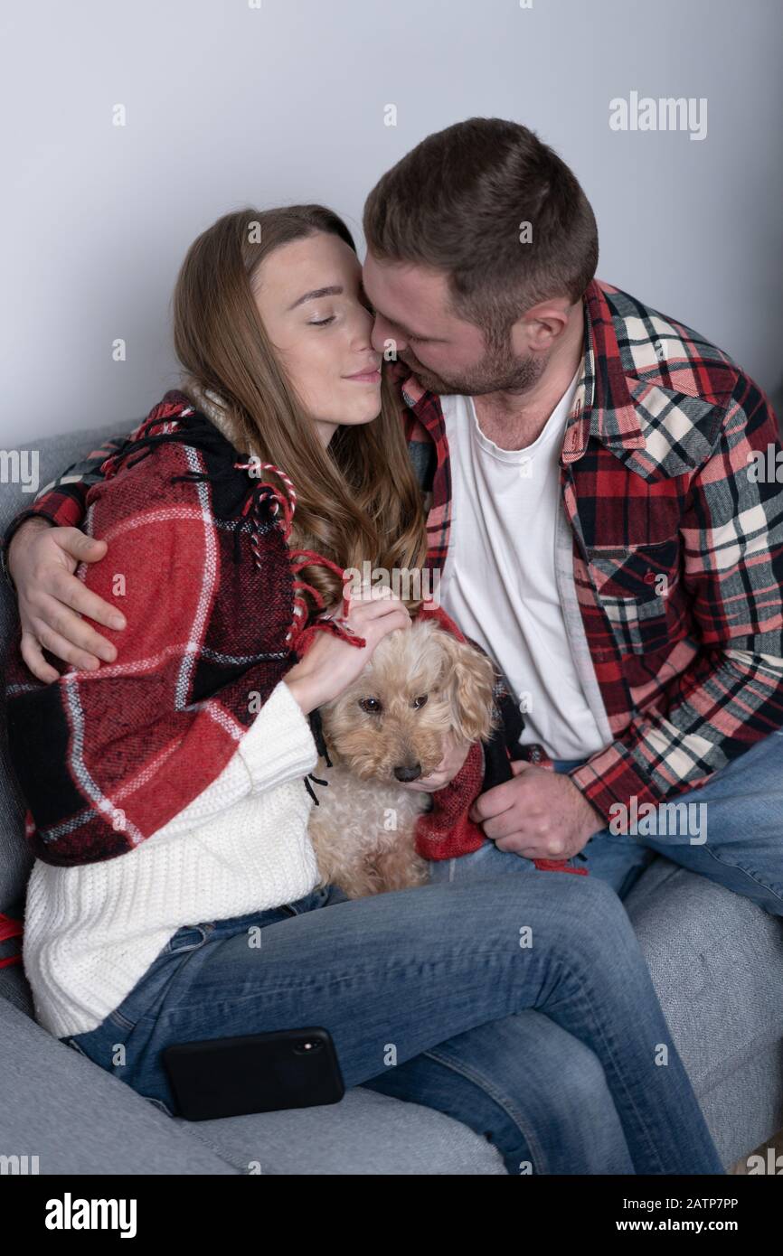 Happy couple with fluffy dog kissing on sofa Stock Photo - Alamy