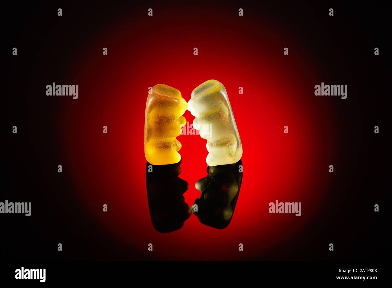 Two gummy bears kissing under the red spotlight. Love, emotion and ...