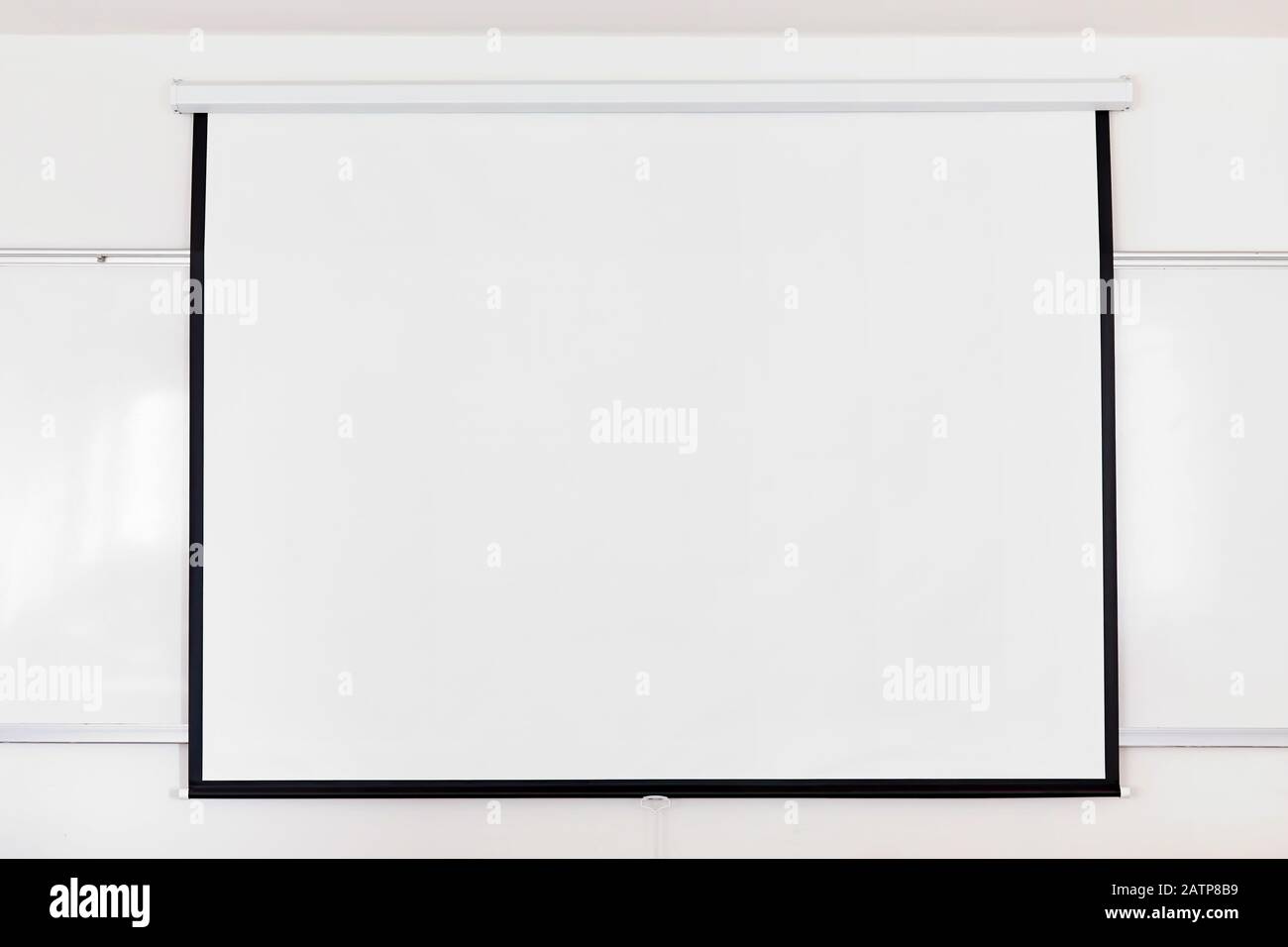 White projection screen over a white board on the classroom wall. Close ...