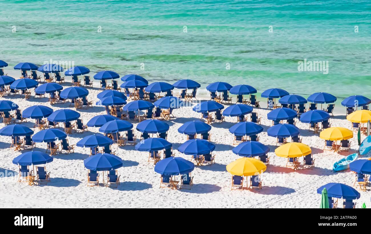 Beachfront umbrellas. Blue and Yellow with sea kayak and paddle boards ...