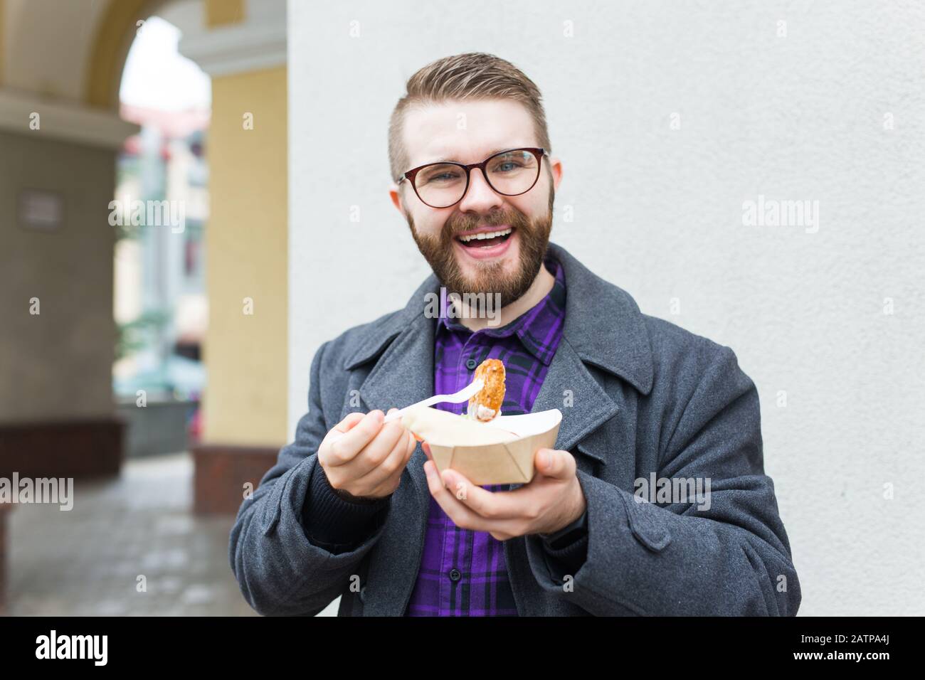 Fast food and meal concept - Young man eating take away food on the ...