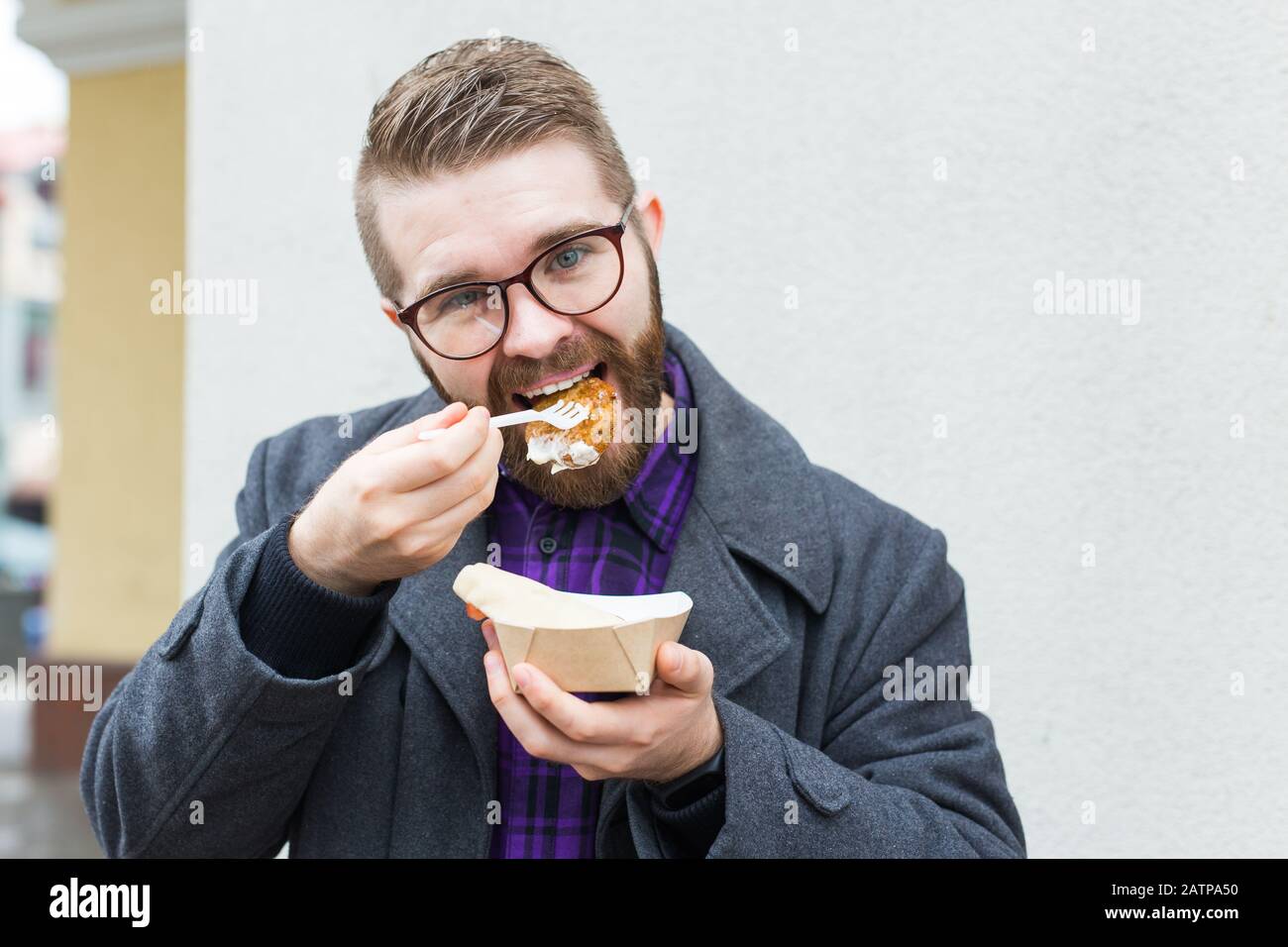 Fast food and meal concept - Young man eating take away food on the ...