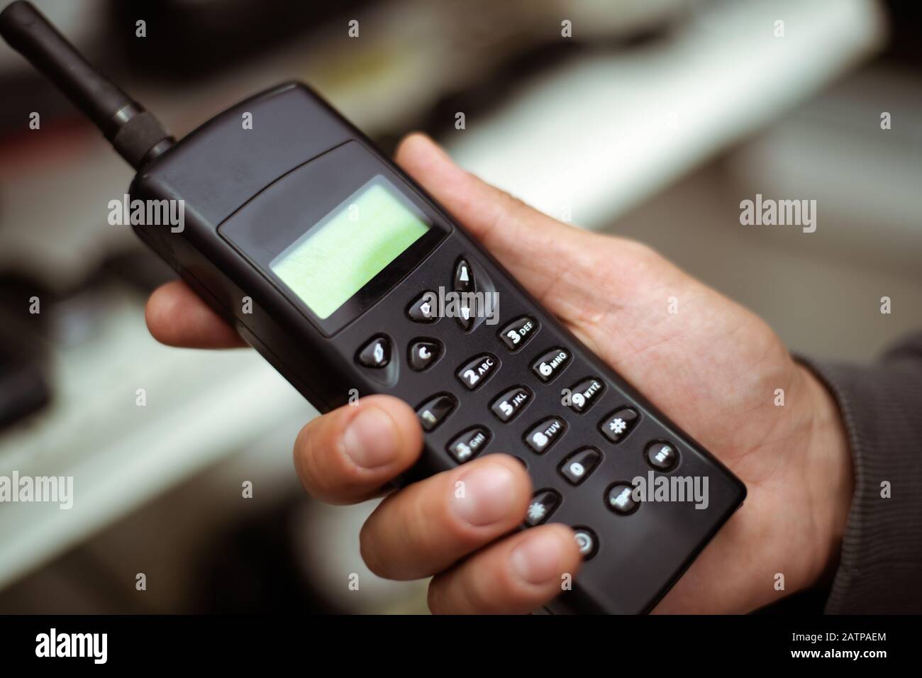 Male hand holds a black plastic vintage cell or radio telephone ...