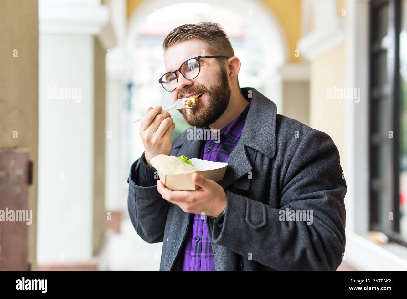 Fast food and meal concept - Young man eating take away food on the ...