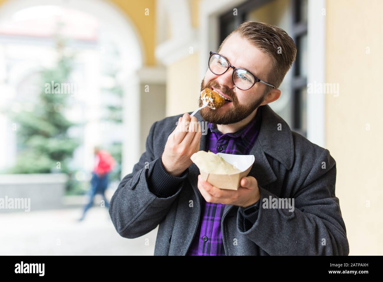 Fast food and meal concept - Young man eating take away food on the ...