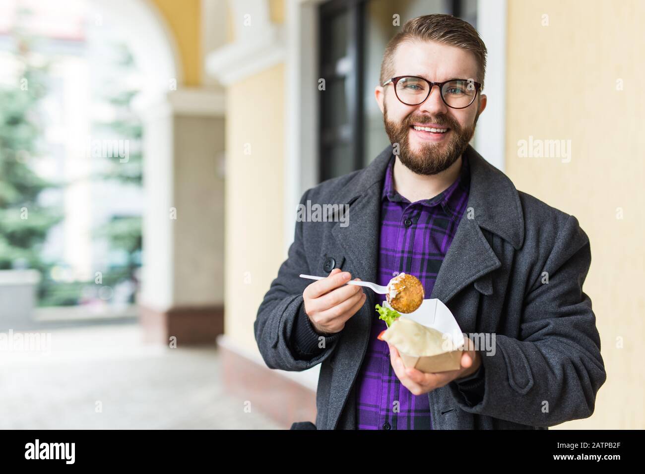 Fast food and meal concept - Young man eating take away food on the ...