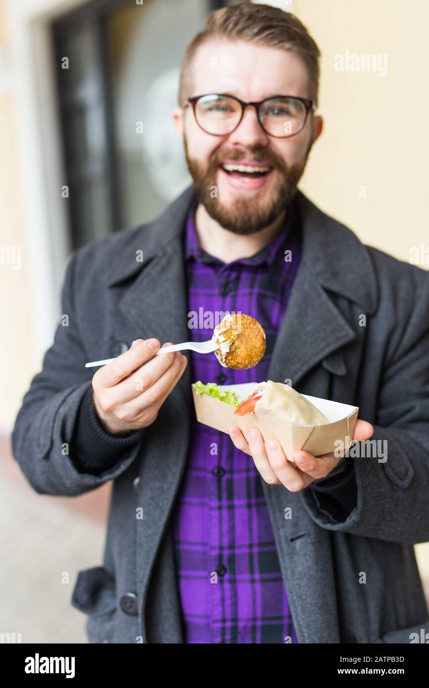 Fast food and meal concept - Young man eating take away food on the ...