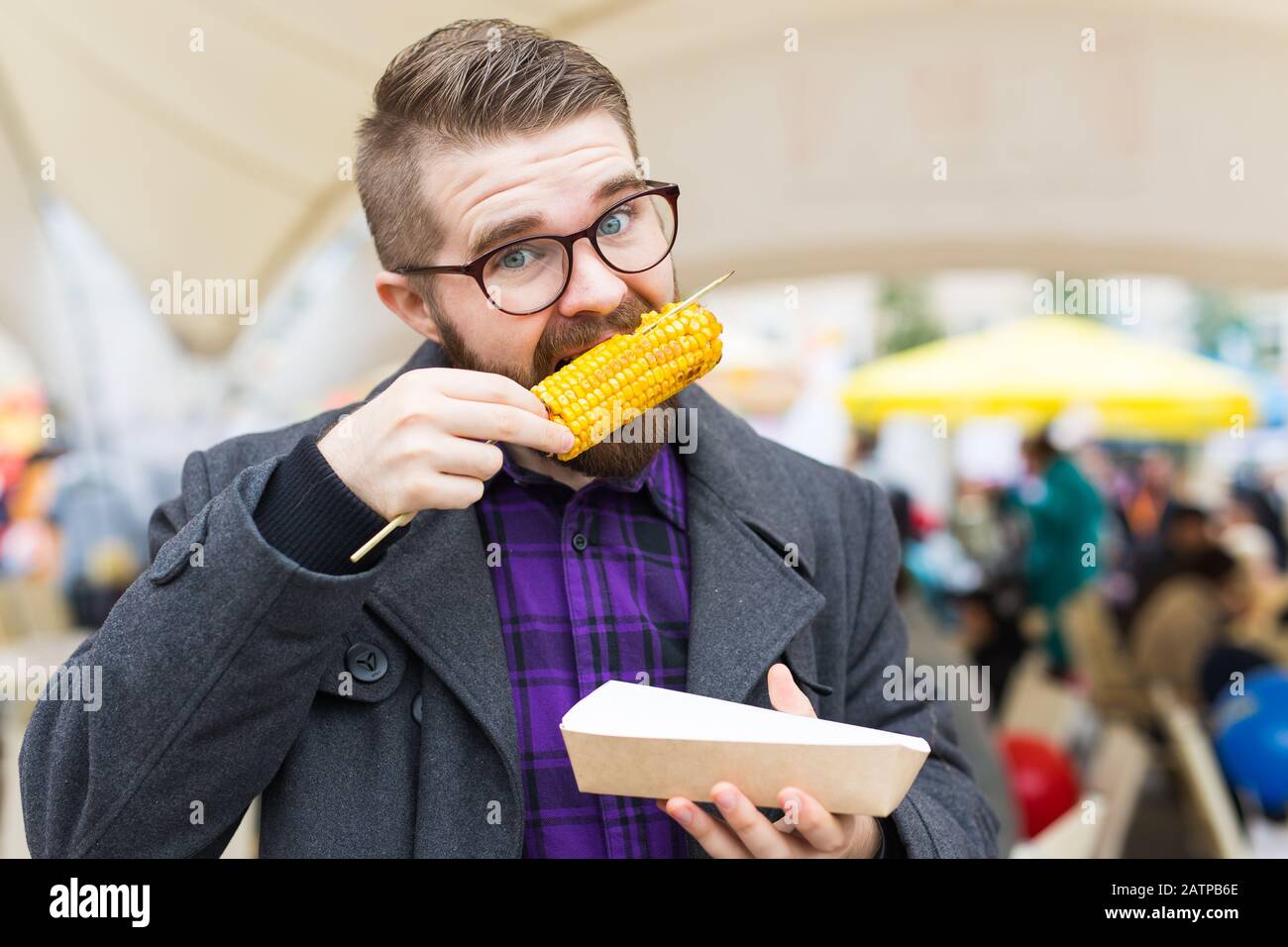 Handsome man eating roasted corn on the street Stock Photo - Alamy