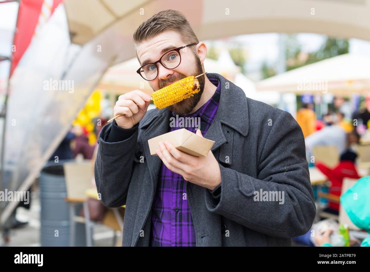 Handsome man eating street food corn at fast food festival Stock Photo ...