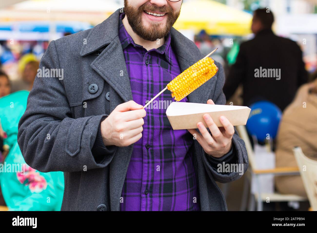Handsome man eating street food corn at fast food festival Stock Photo ...