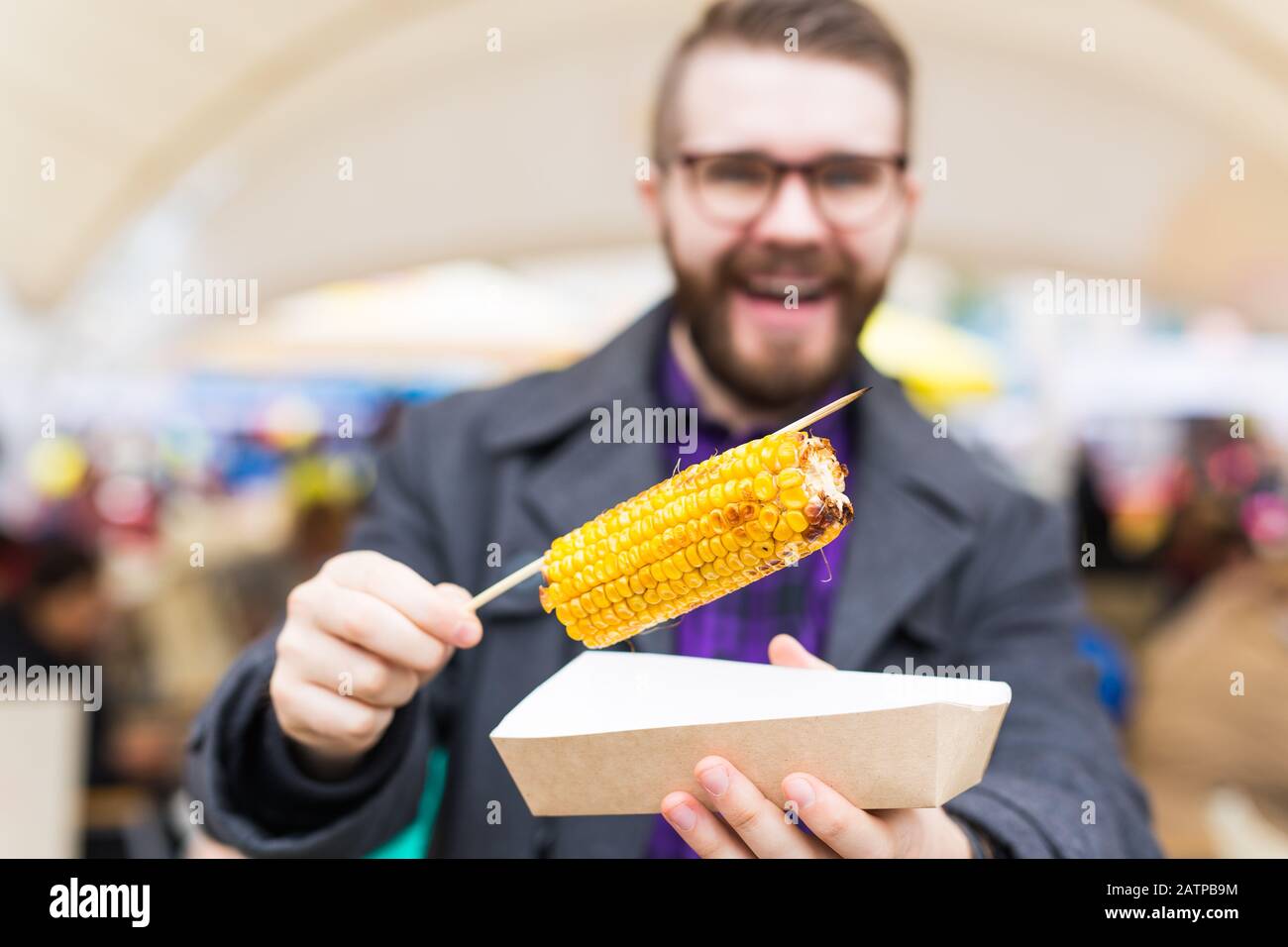 Man eating grilled corn. vegetarian food. healthy and tasty vegetables ...