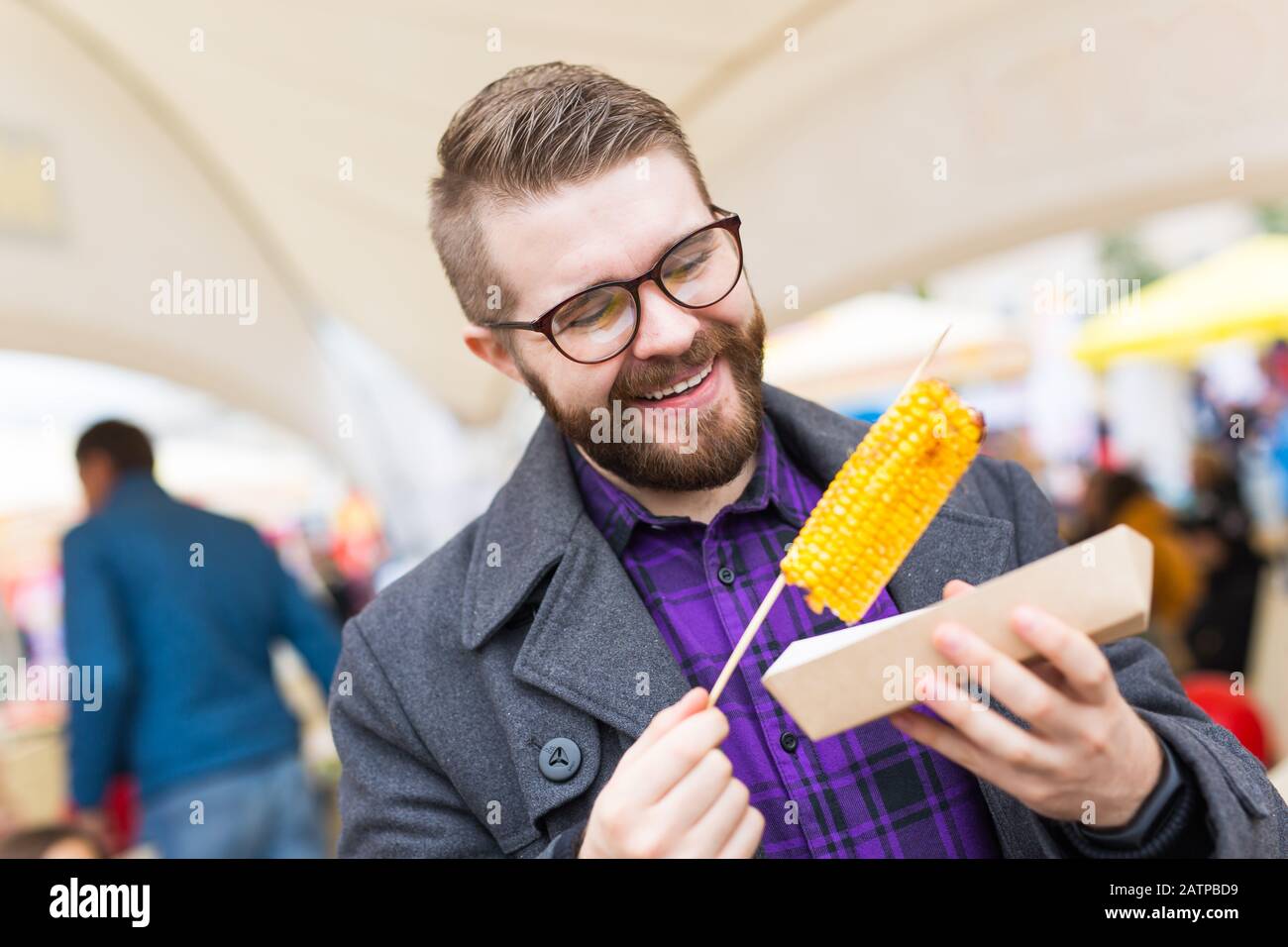 Handsome man eating roasted corn on the street Stock Photo - Alamy