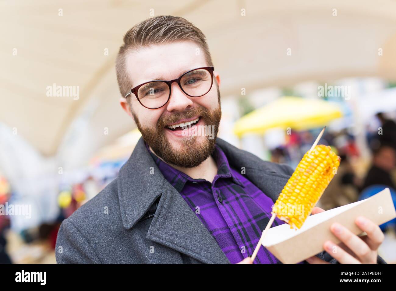 Man eating grilled corn. vegetarian food. healthy and tasty vegetables ...