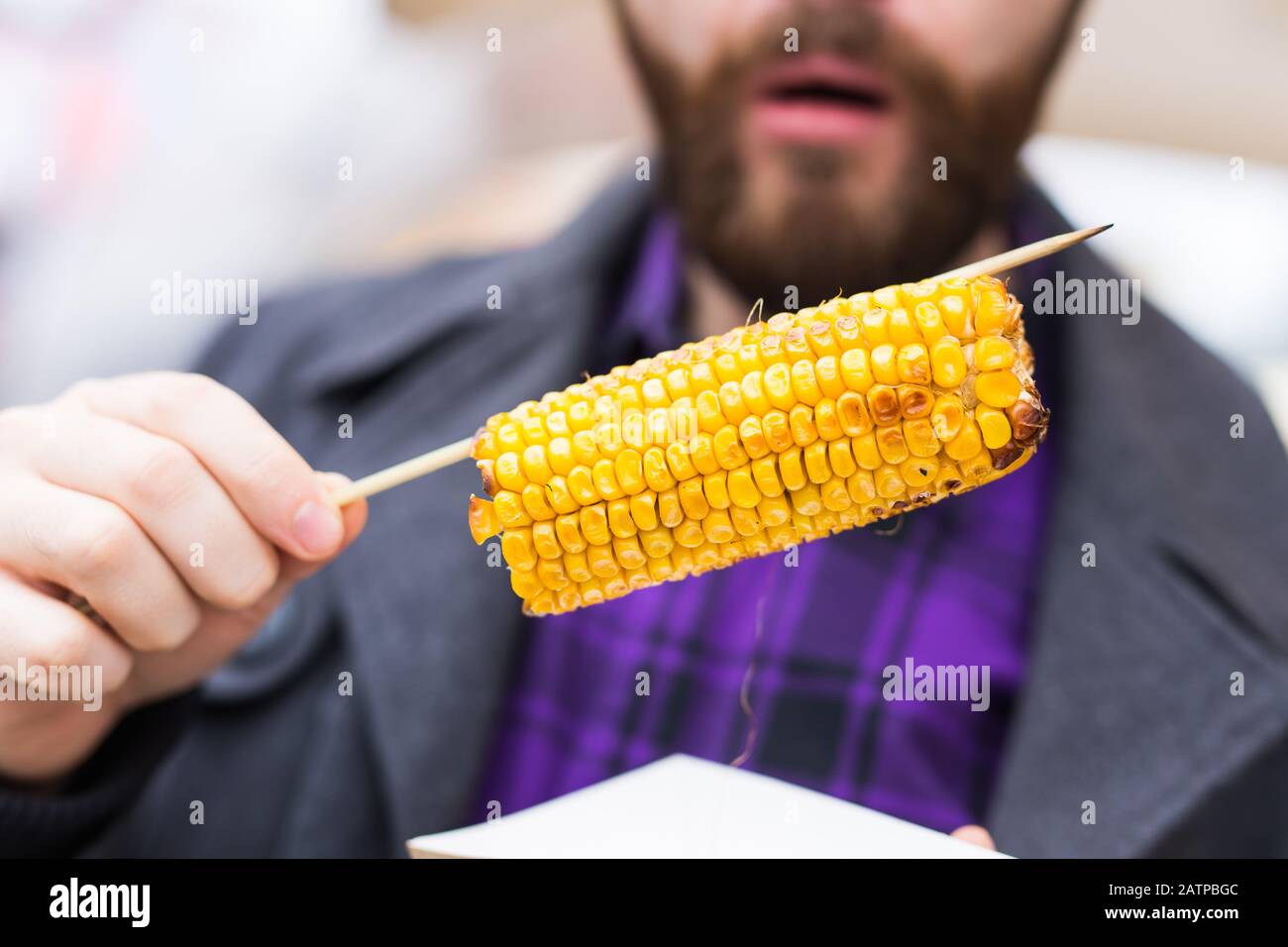 Handsome man eating a delicious corn cob on the street Stock Photo - Alamy