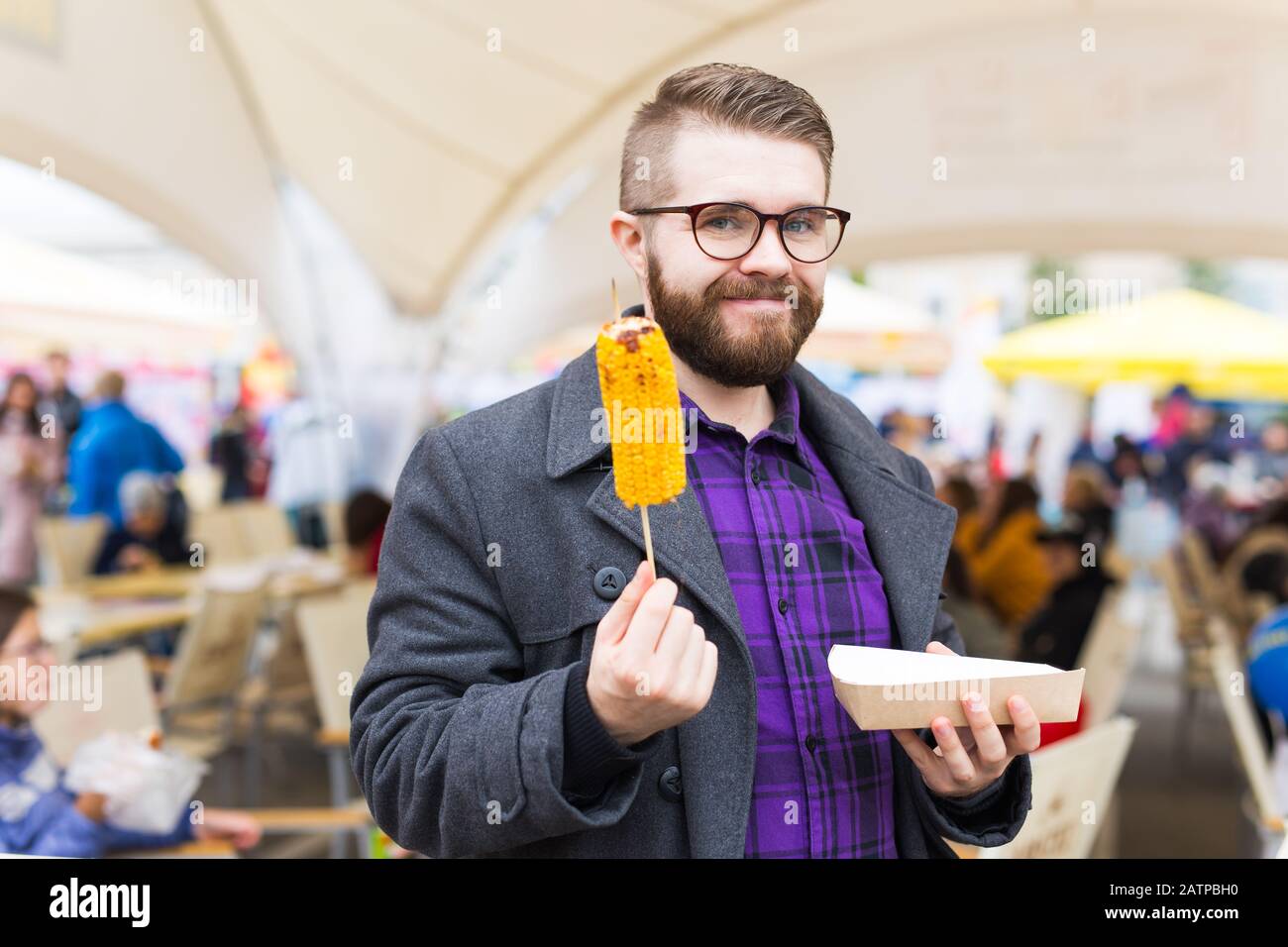 Handsome man eating street food corn at fast food festival Stock Photo ...