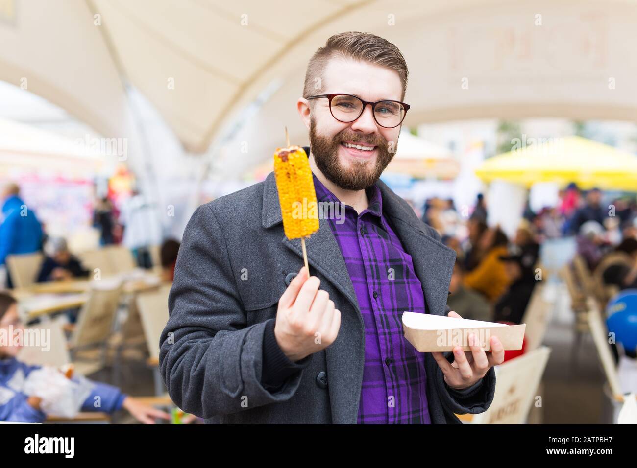 Handsome man eating street food corn at fast food festival Stock Photo ...