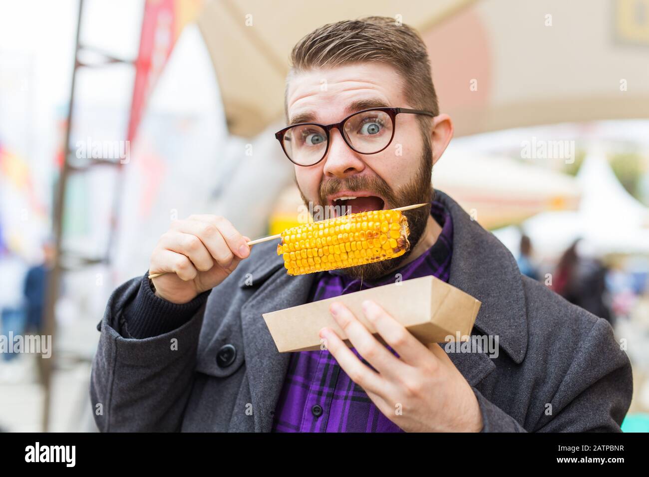 Handsome man eating roasted corn on the street Stock Photo - Alamy