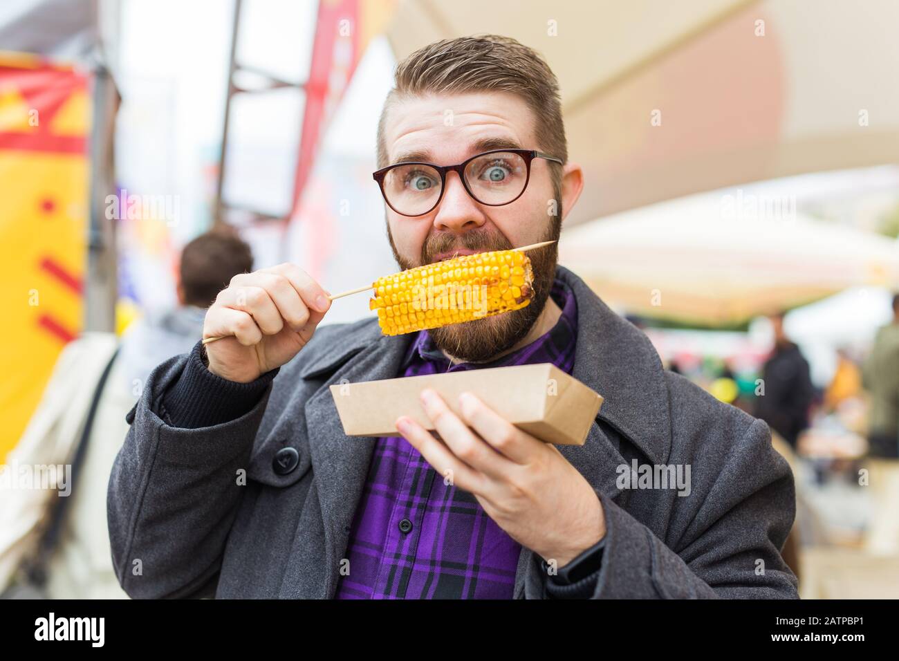 Handsome man eating street food corn at fast food festival Stock Photo ...