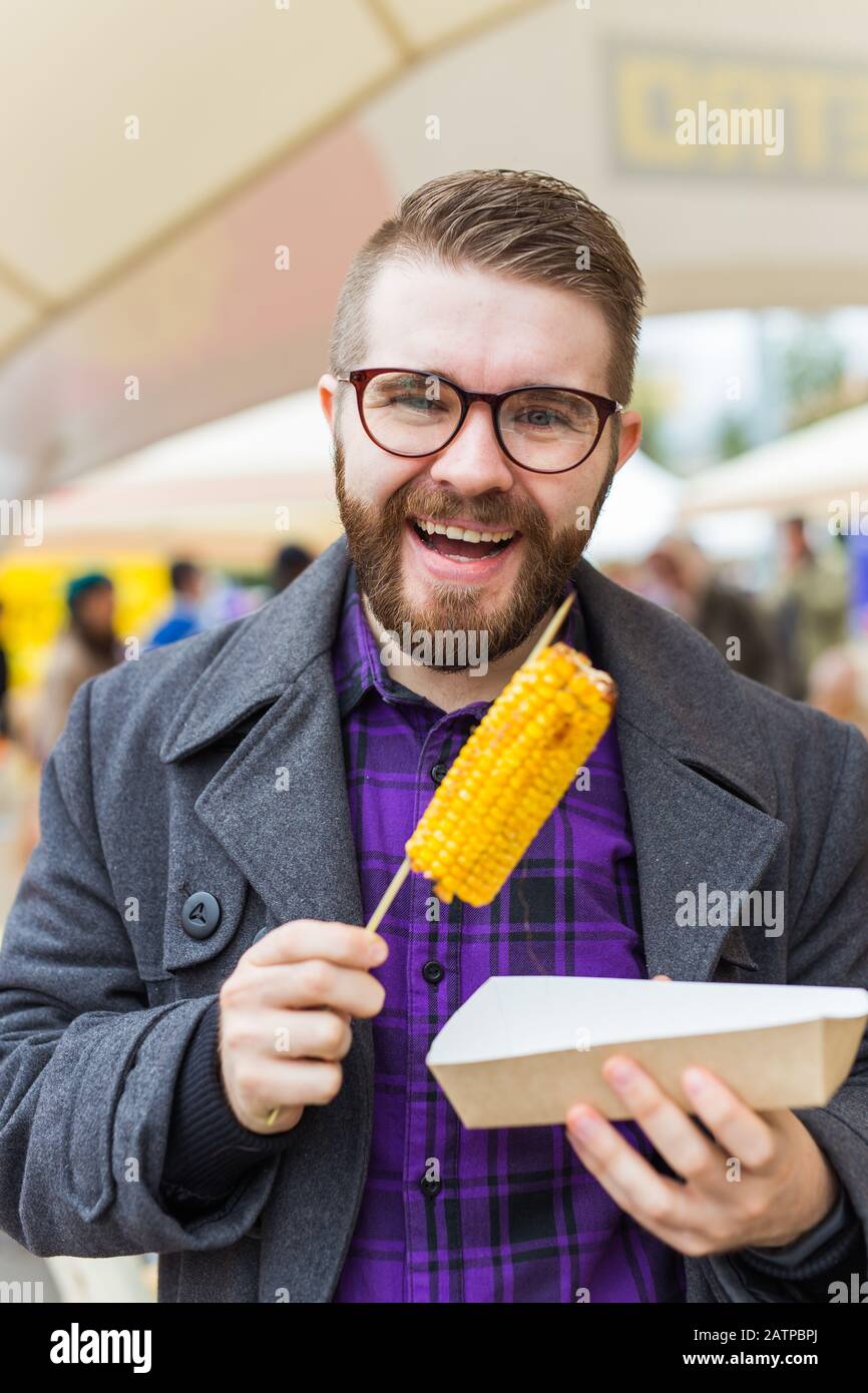 Handsome man eating roasted corn on the street Stock Photo - Alamy