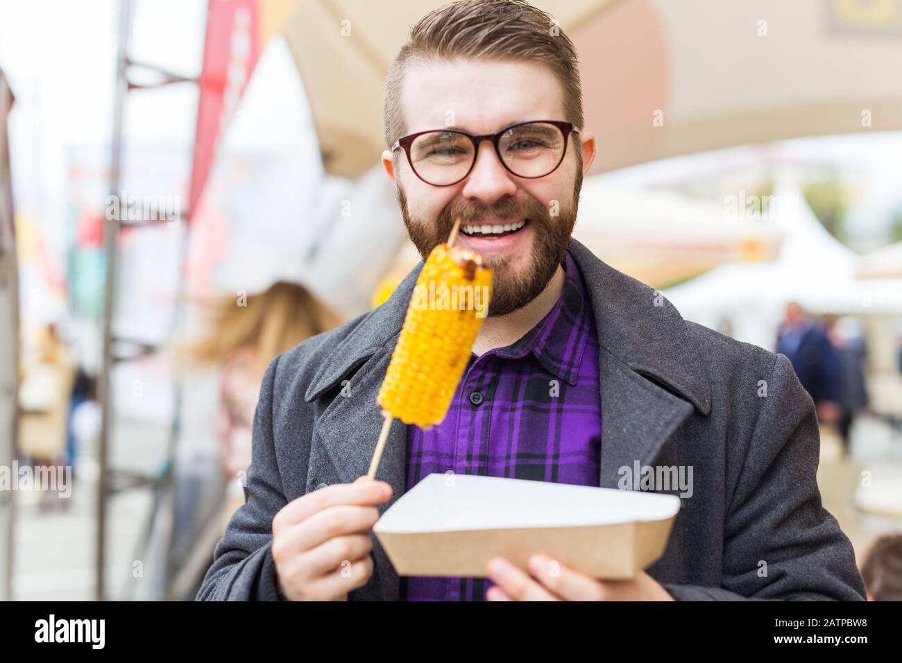 Handsome man eating roasted corn on the street Stock Photo - Alamy