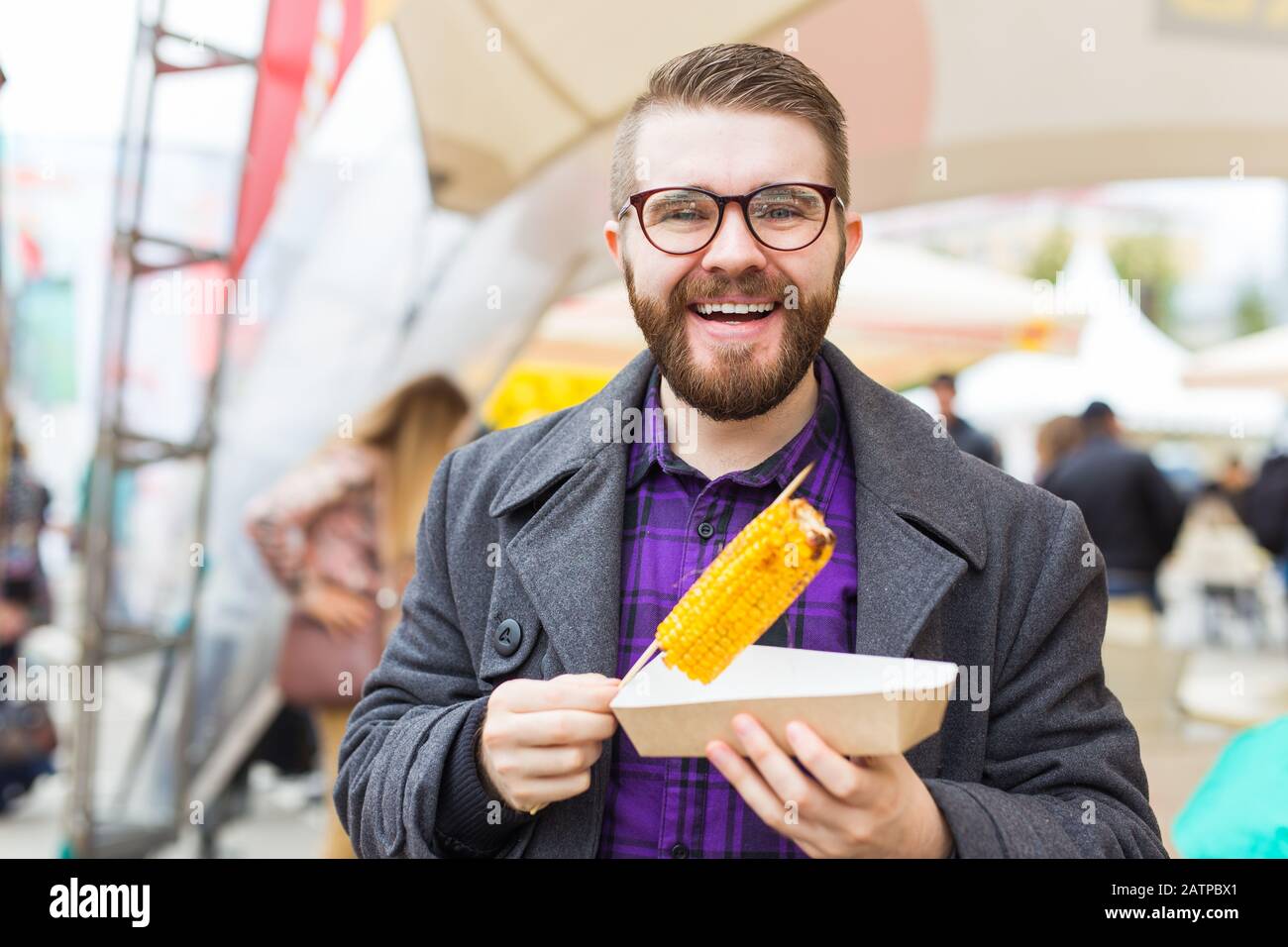 Handsome man eating street food corn at fast food festival Stock Photo ...