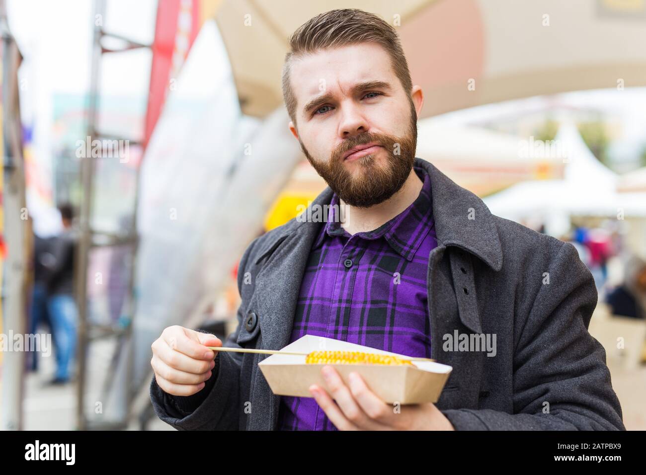 Handsome man eating street food corn at fast food festival Stock Photo ...